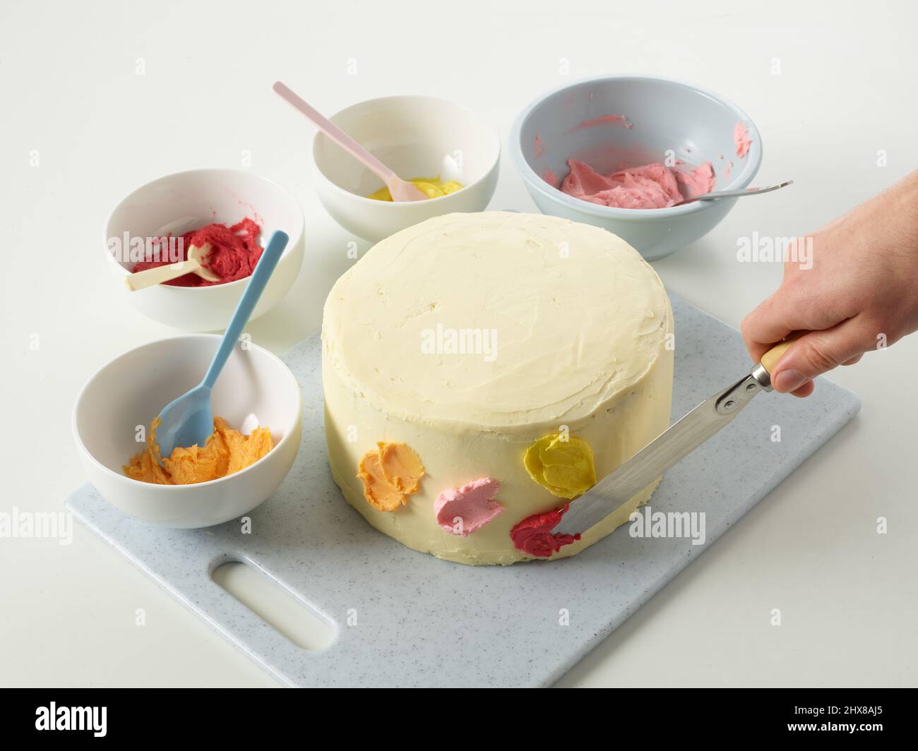 Placing splodges of different coloured icing on a rose and almond cake ...