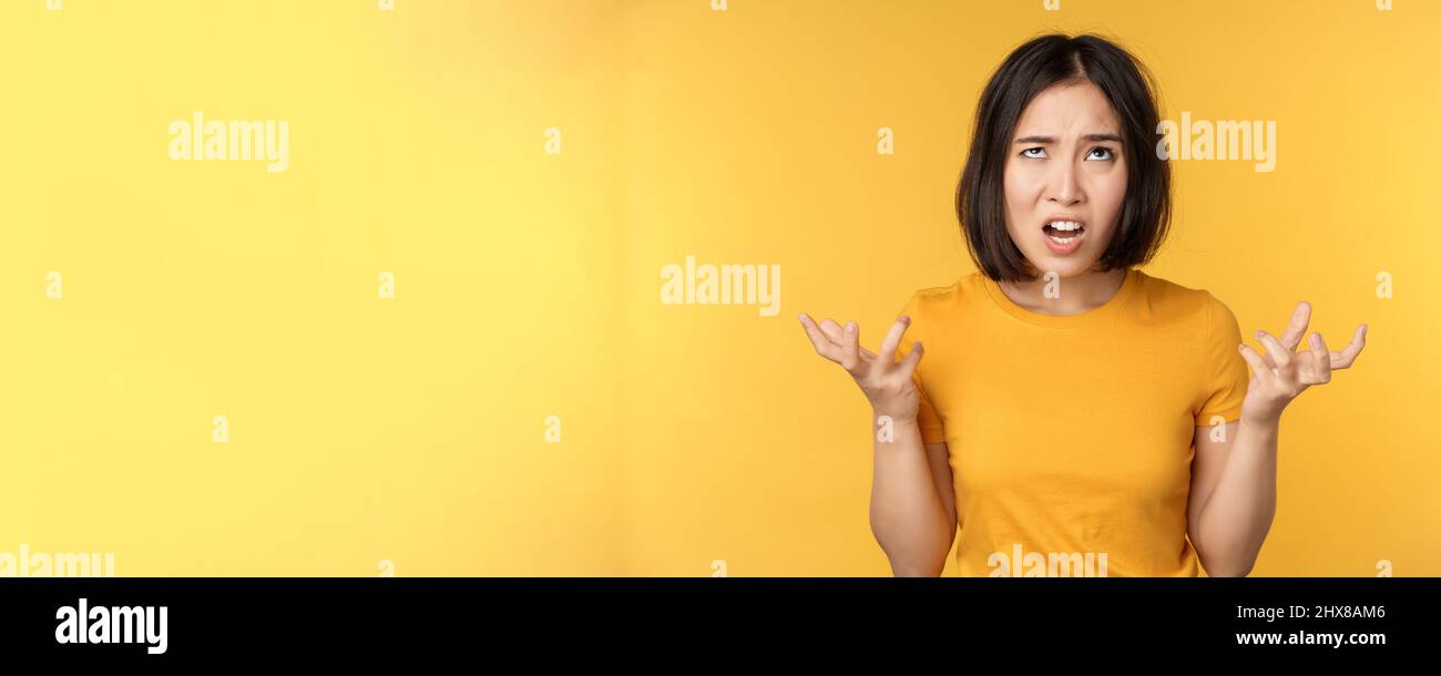 Image of angry asian woman, shouting and cursing, looking outraged ...