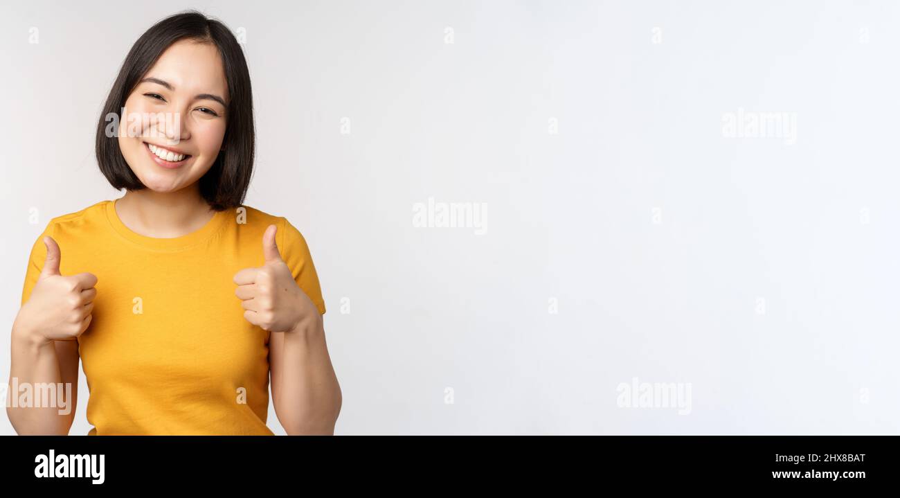 Beautiful smiling asian female model, showing thumbs up and looking ...