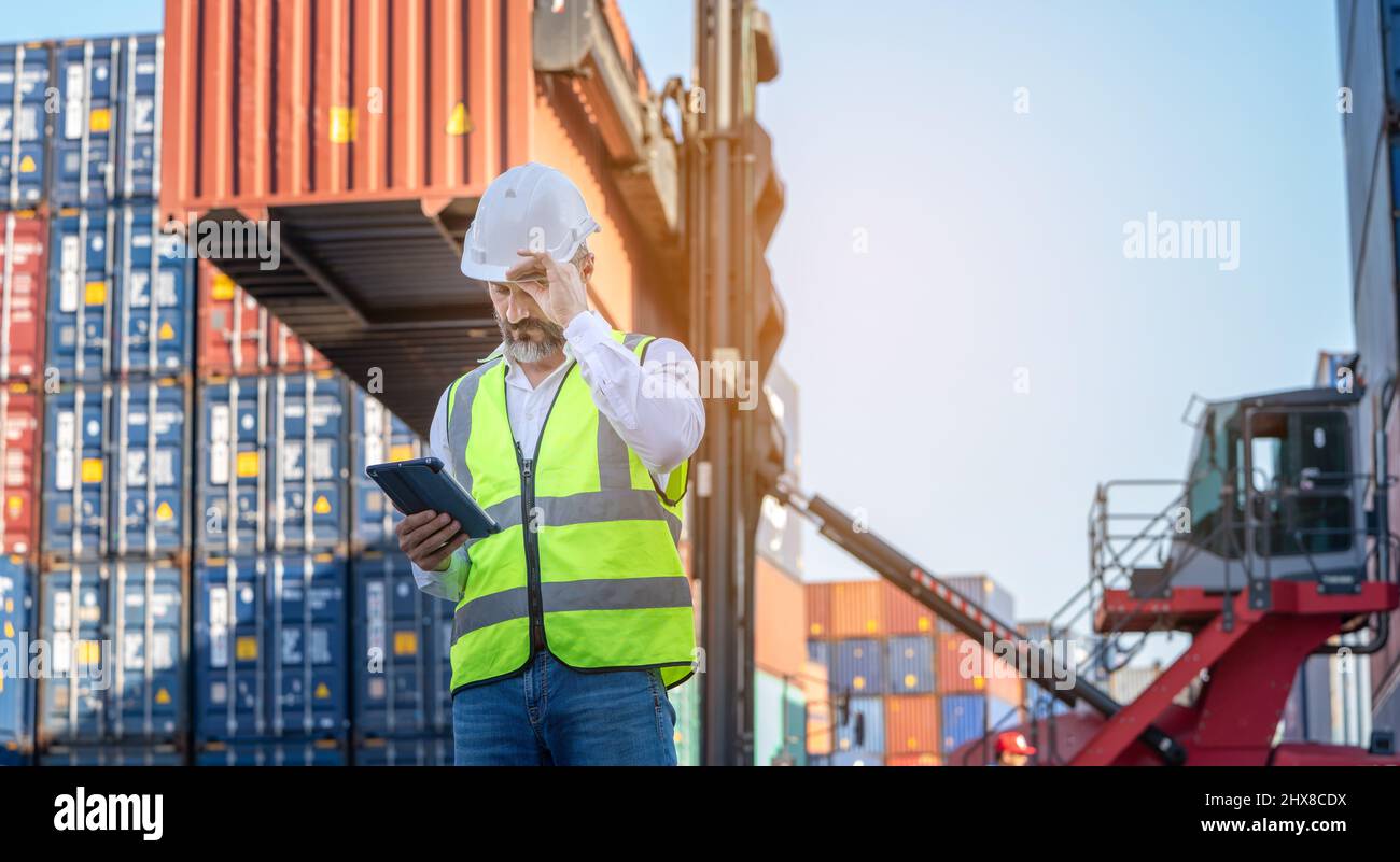 CEO or Manager in white helmet with tablet control loading Containers box in warehouse , manager ...