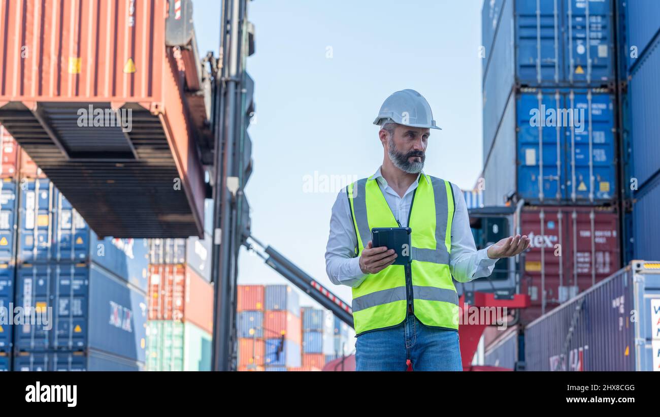 CEO or Manager in white helmet with tablet control loading Containers ...