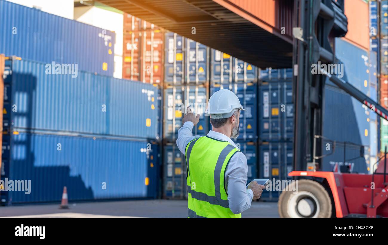CEO or Manager in white helmet with tablet control loading Containers box in warehouse , manager ...