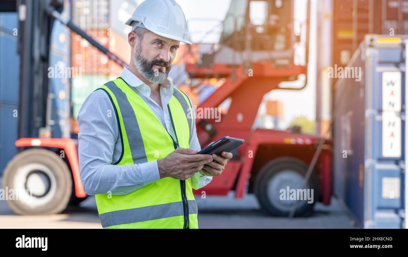 CEO or Manager in white helmet with tablet control loading Containers ...