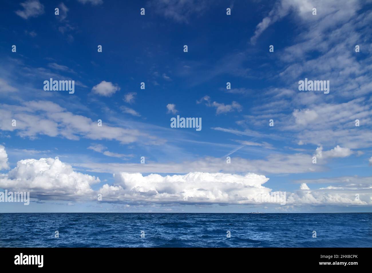 on the sea - blue water under blue sky with a ship in the far distance ...