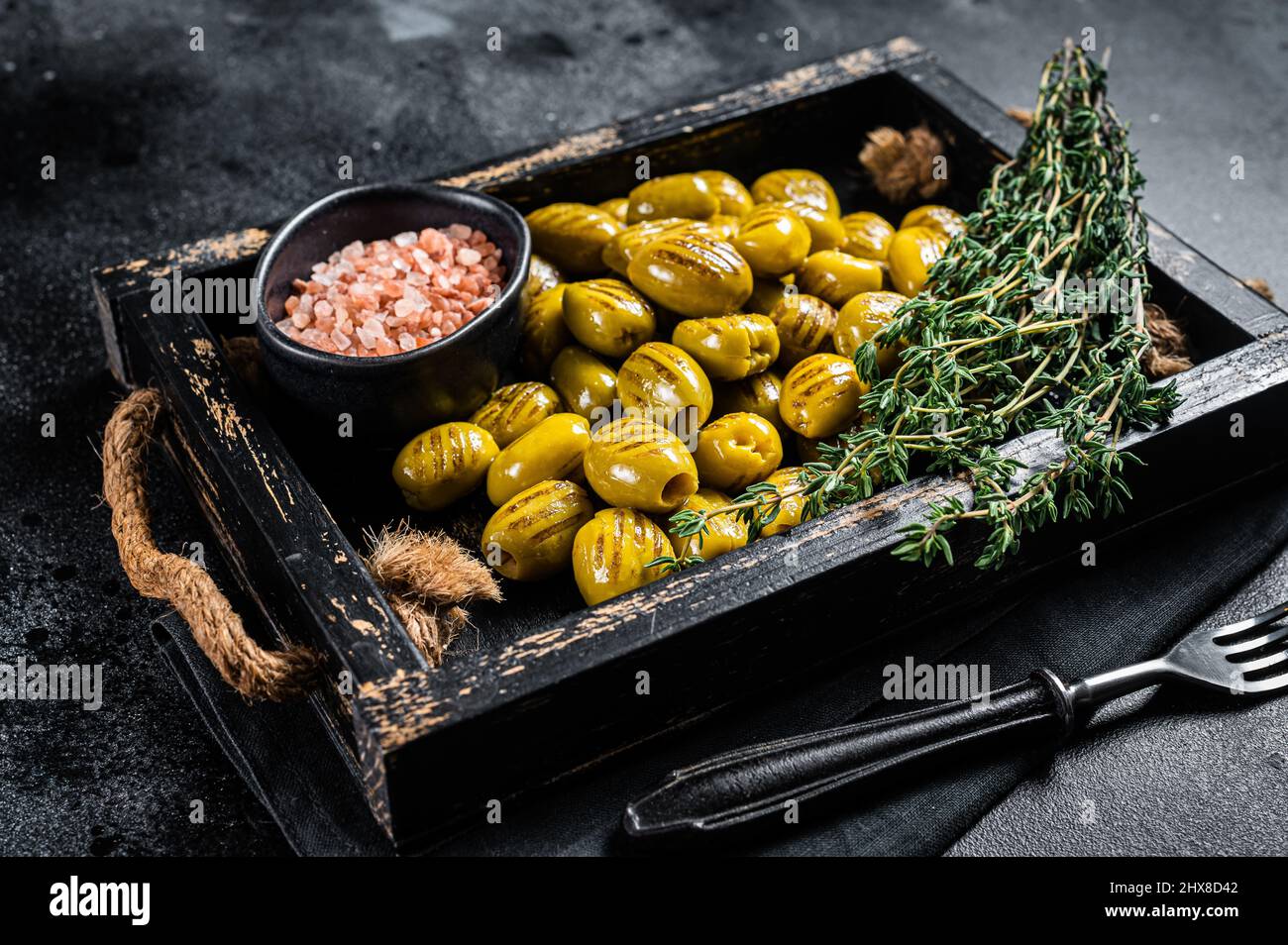 Greek Grilled olives with garlic, olive oil and spices in wooden tray ...