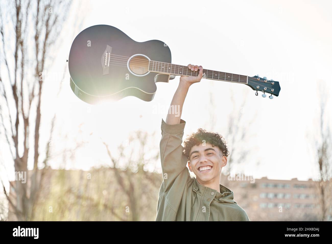 Man with happy face holding guitar above his head. Concept of rock ...