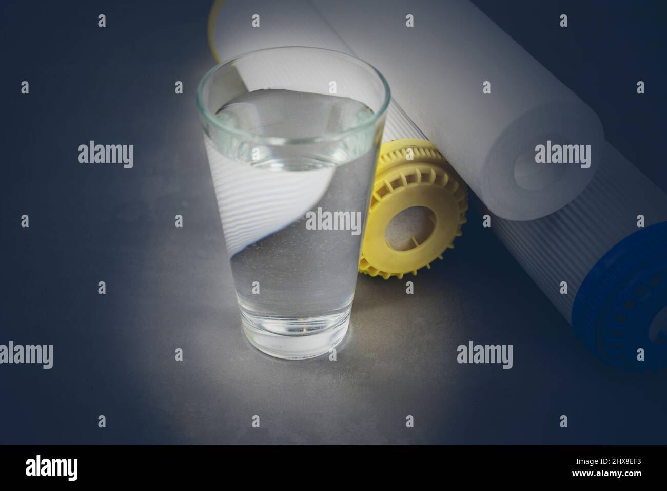 A glass of clean water next to the water purification filter. The ...