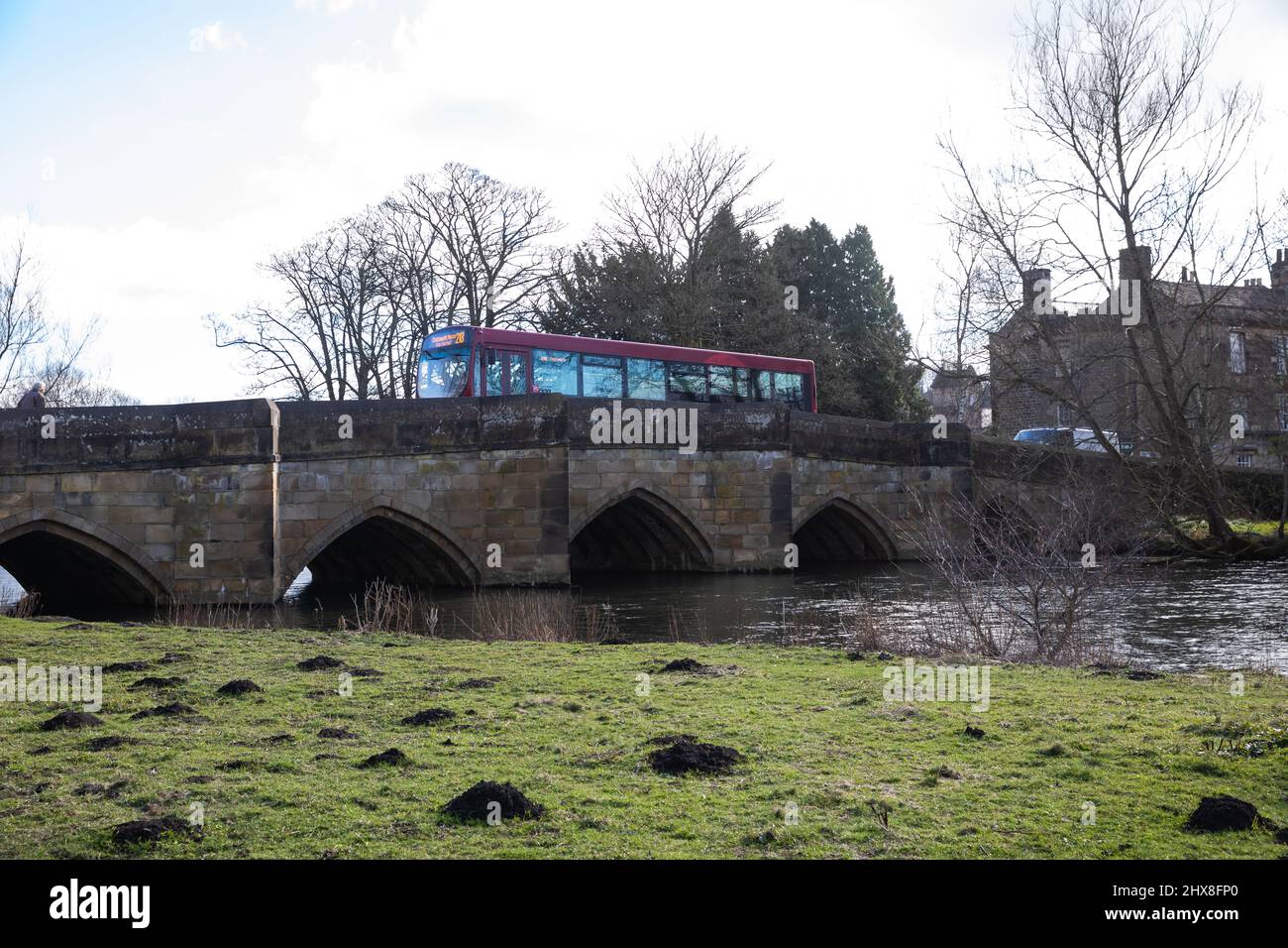 A red single decker bus crosses the bridge in Bakewell, Derbyshire, UK ...