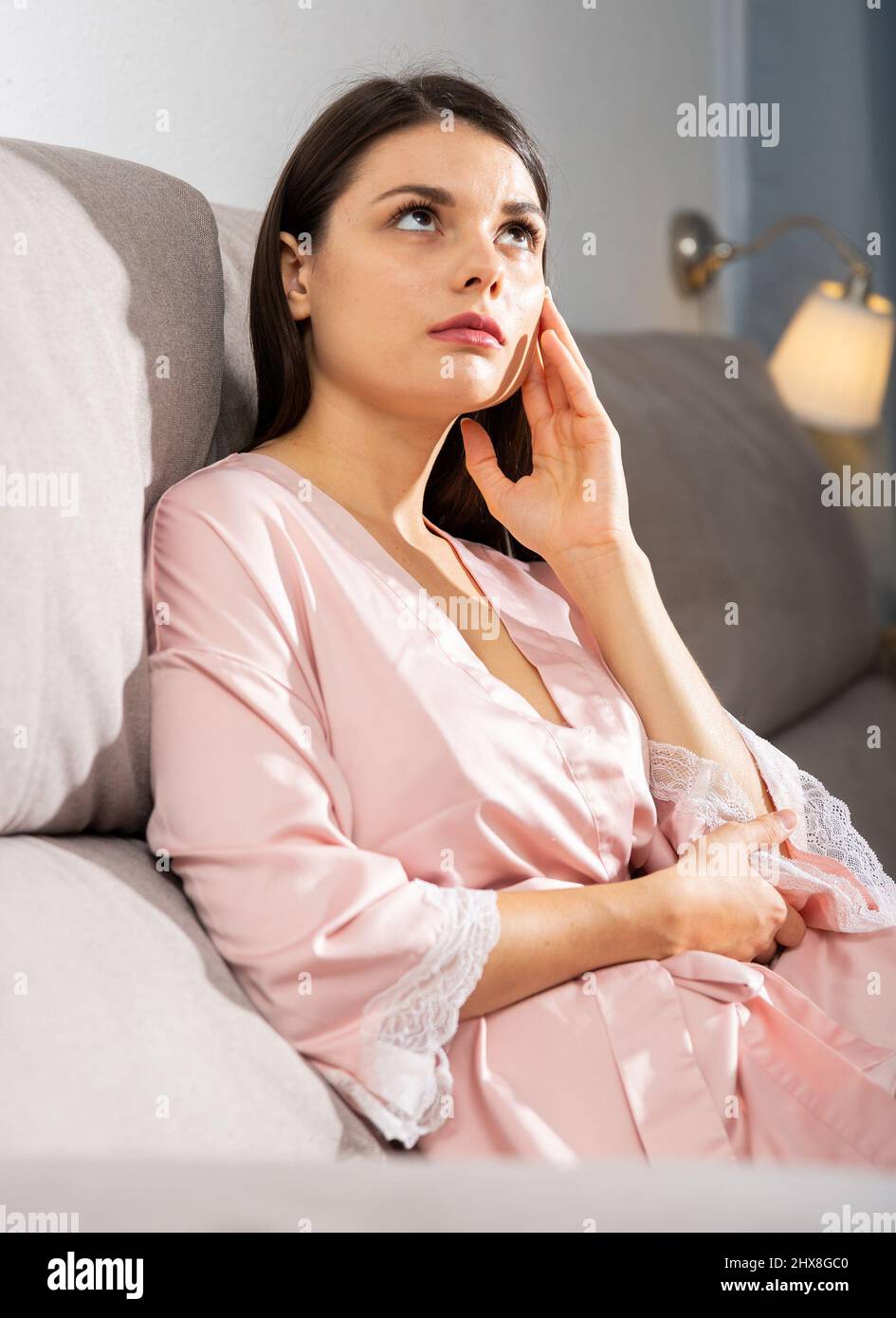 Disappointed girl sitting on sofa in living room Stock Photo - Alamy