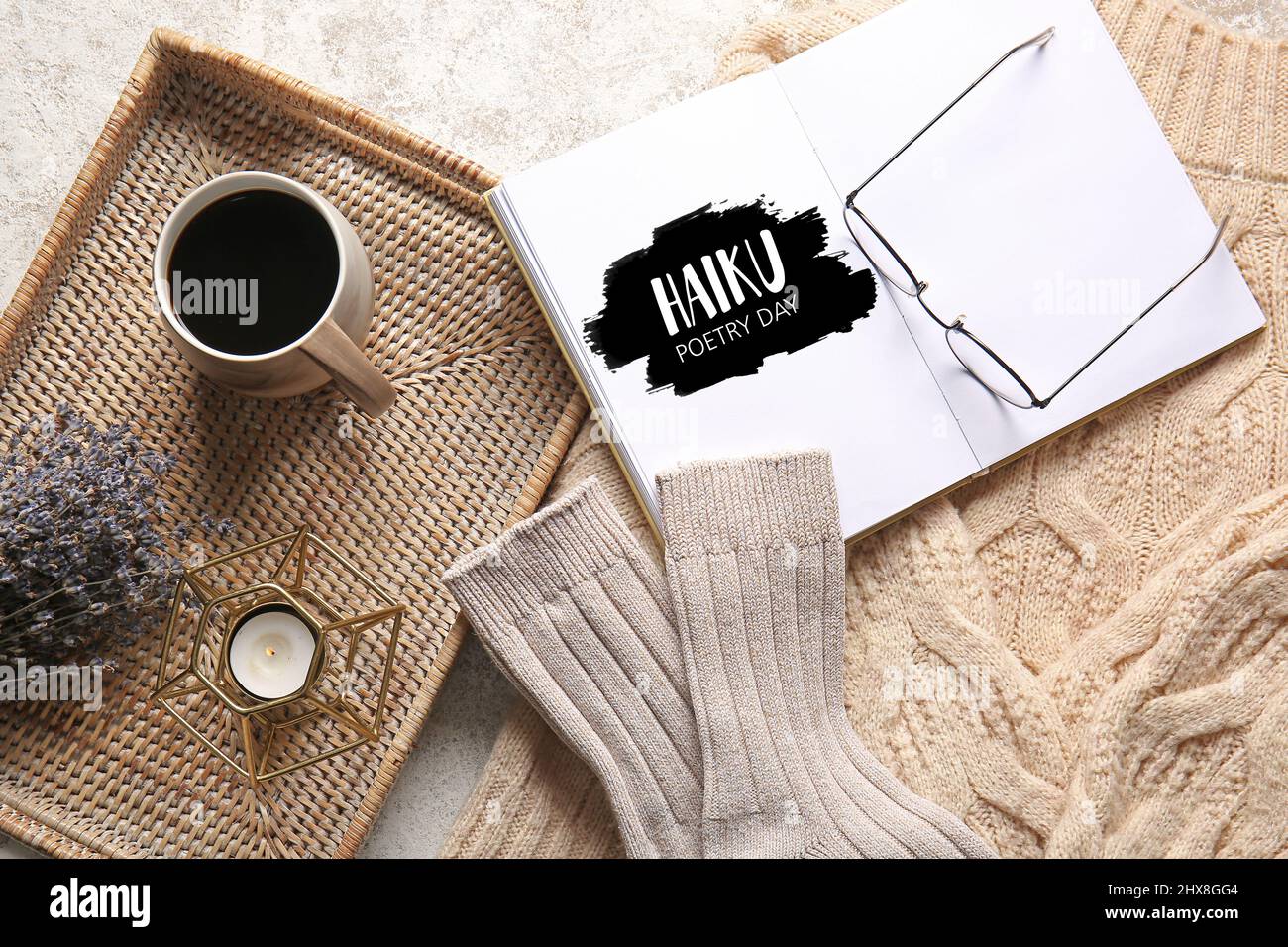 Book with text HAIKU POETRY DAY, warm clothes and cup of coffee on ...