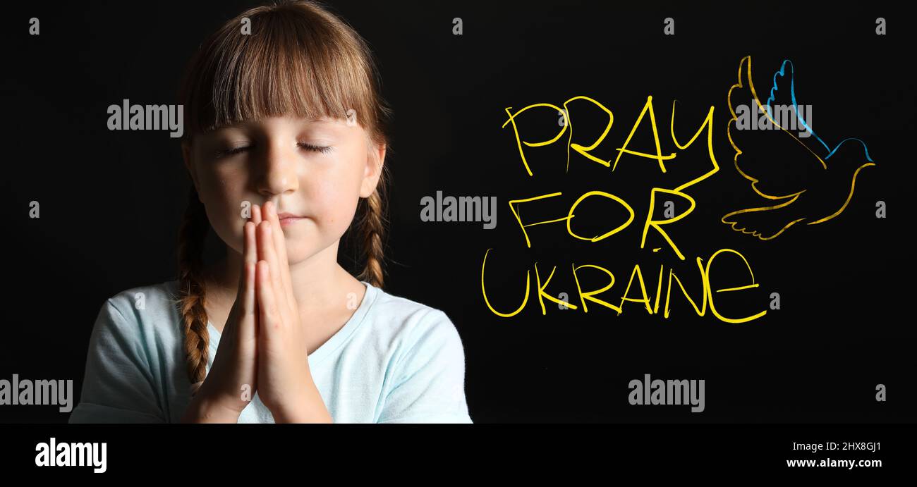 Religious little girl and text PRAY FOR UKRAINE on dark background ...