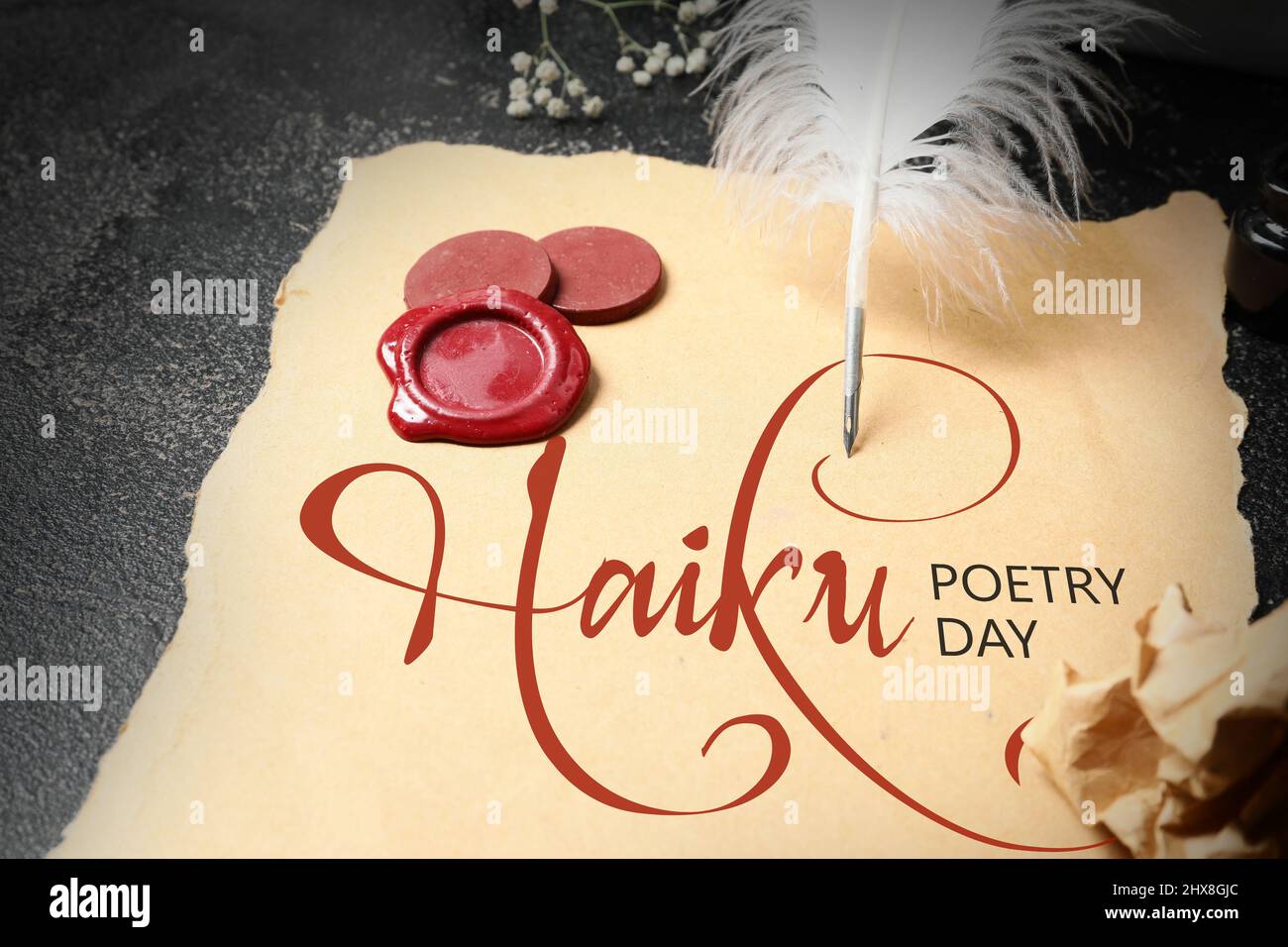 Paper sheet with text HAIKU POETRY DAY and feather pen on dark ...