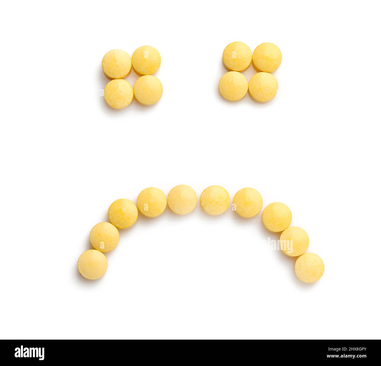 Sad smiley made of yellow pills on white background Stock Photo - Alamy