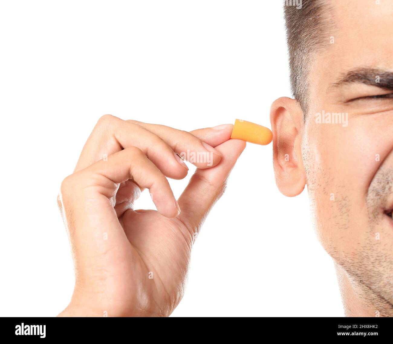 Displeased young man putting ear plug on white background Stock Photo ...