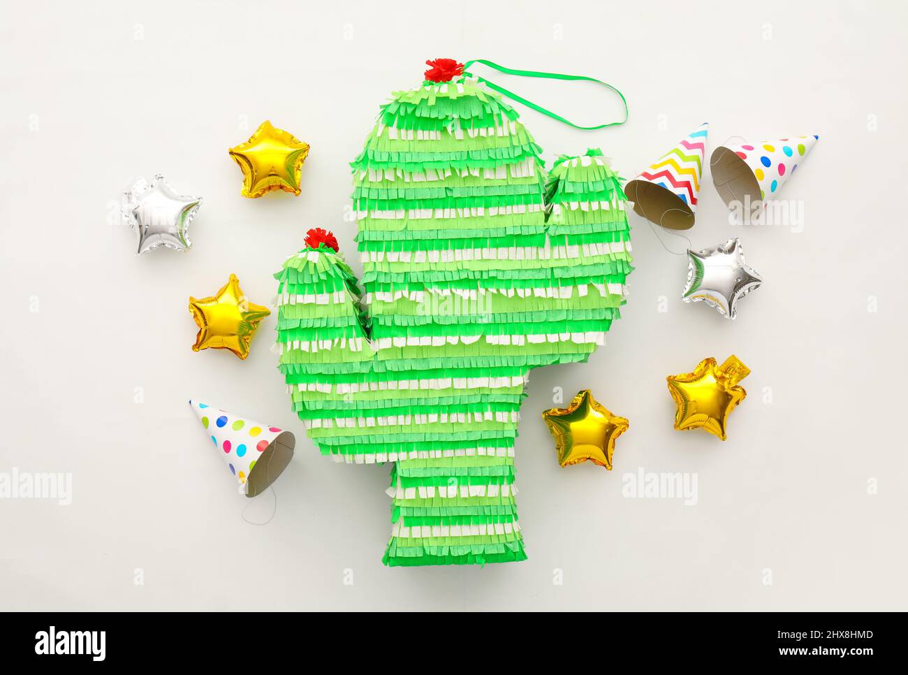 Mexican pinata in shape of cactus with party hats and balloons on white ...