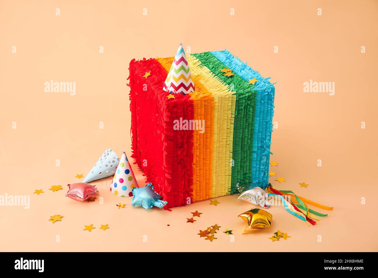 Mexican pinata in shape of cube with party hats and balloons on color ...