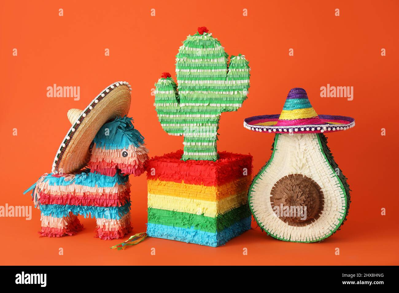 Different Mexican pinatas and sombrero hats on color background Stock ...