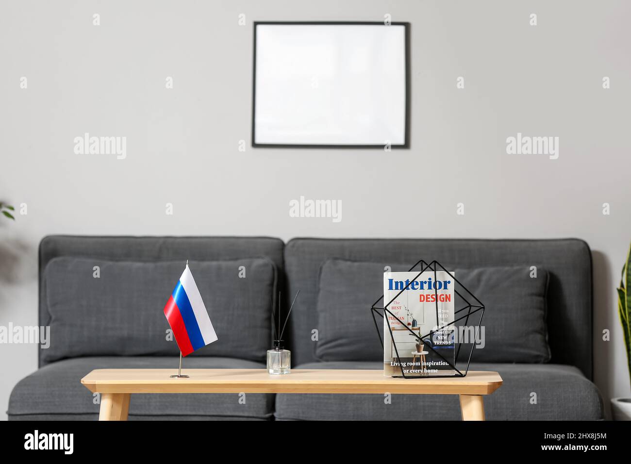 Russian flag on table and blank frame on light wall in room Stock Photo ...
