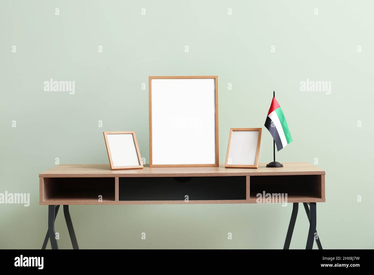 Blank frames and UAE flag on table near green wall Stock Photo - Alamy