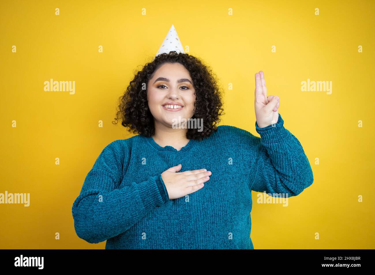 Young beautiful woman wearing a birthday hat over isolated yellow ...