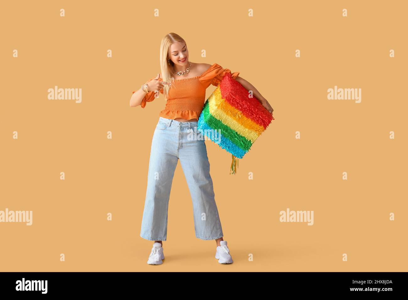 Young woman pointing at Mexican pinata on beige background Stock Photo ...