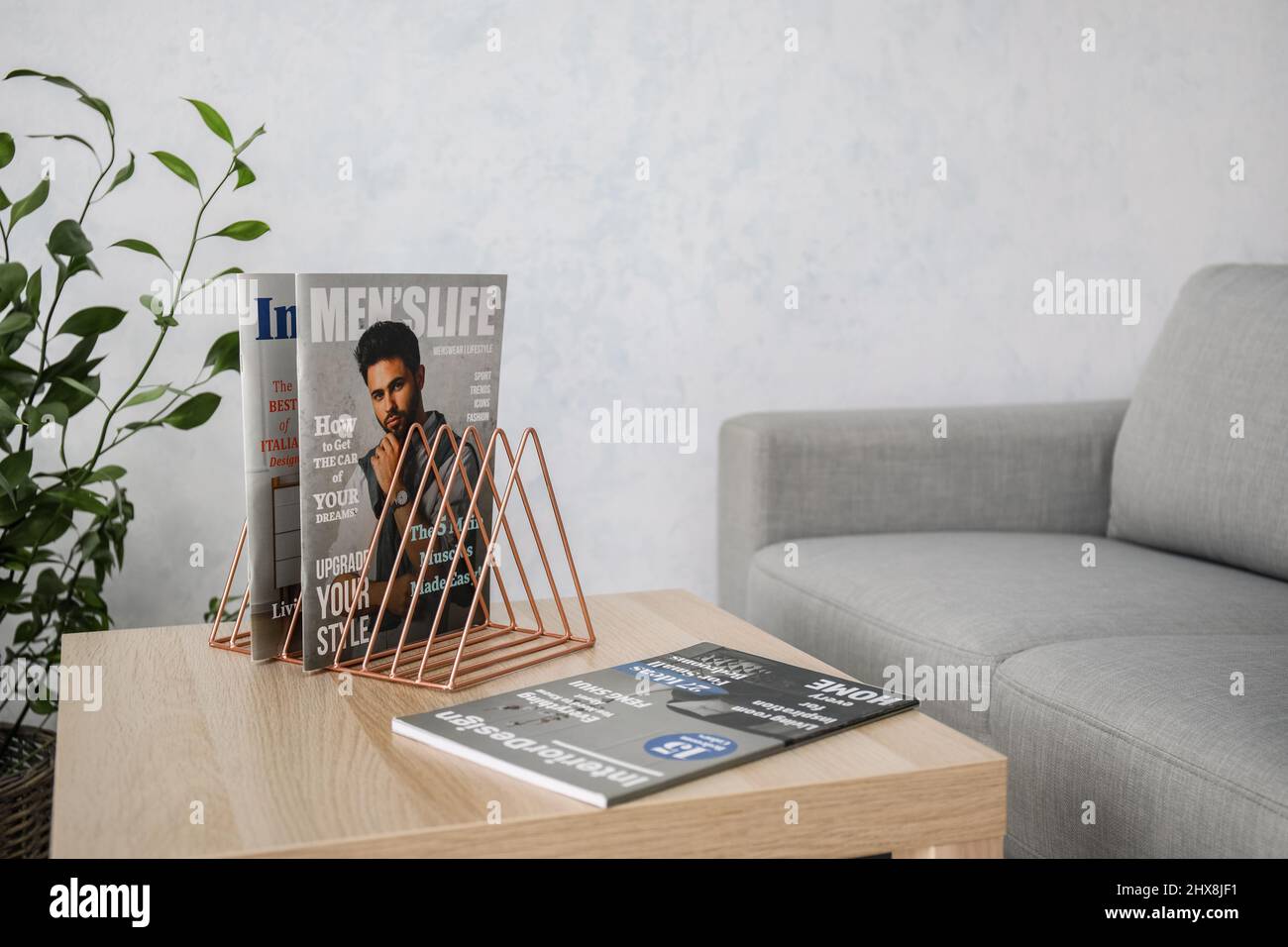 Metal organizer with magazines on table in living room Stock Photo - Alamy