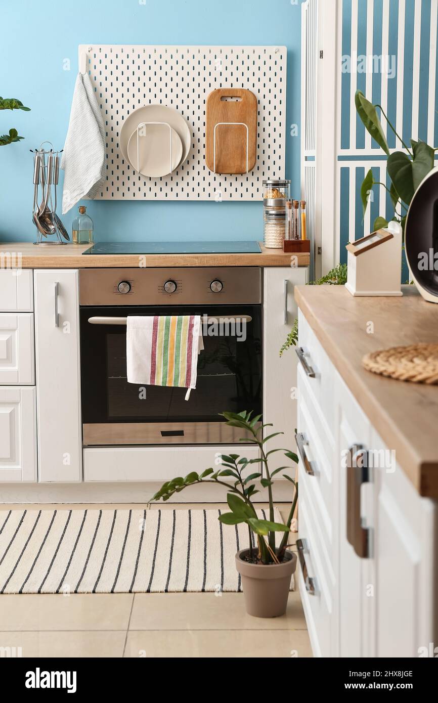 Modern utensils on counter and pegboard with kitchenware on color wall ...