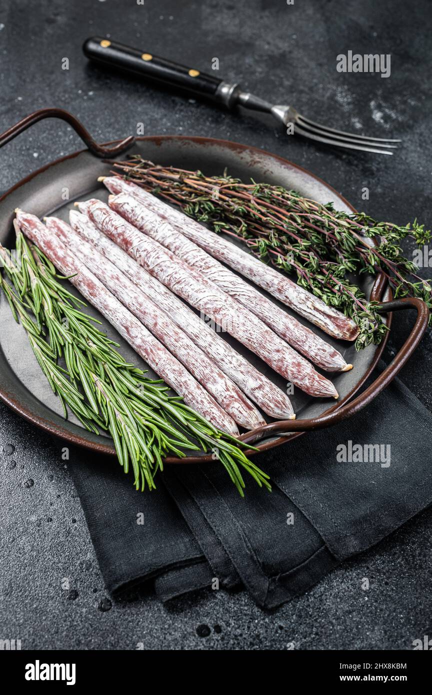 Spanish tapa mini fuet sausage with herbs. Black background. Top view ...