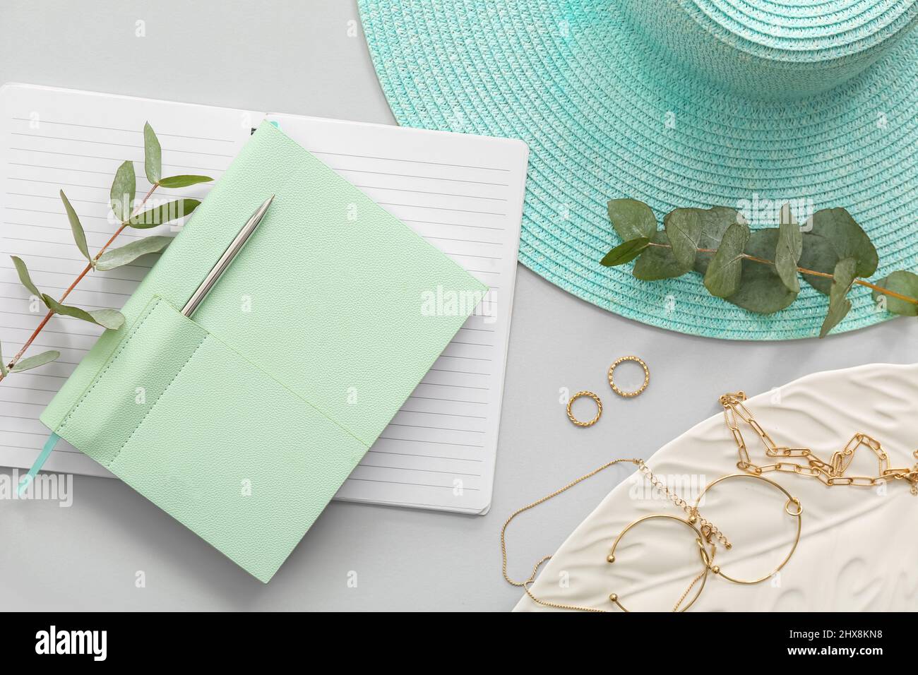 Stylish notebooks with eucalyptus and accessories on light background ...