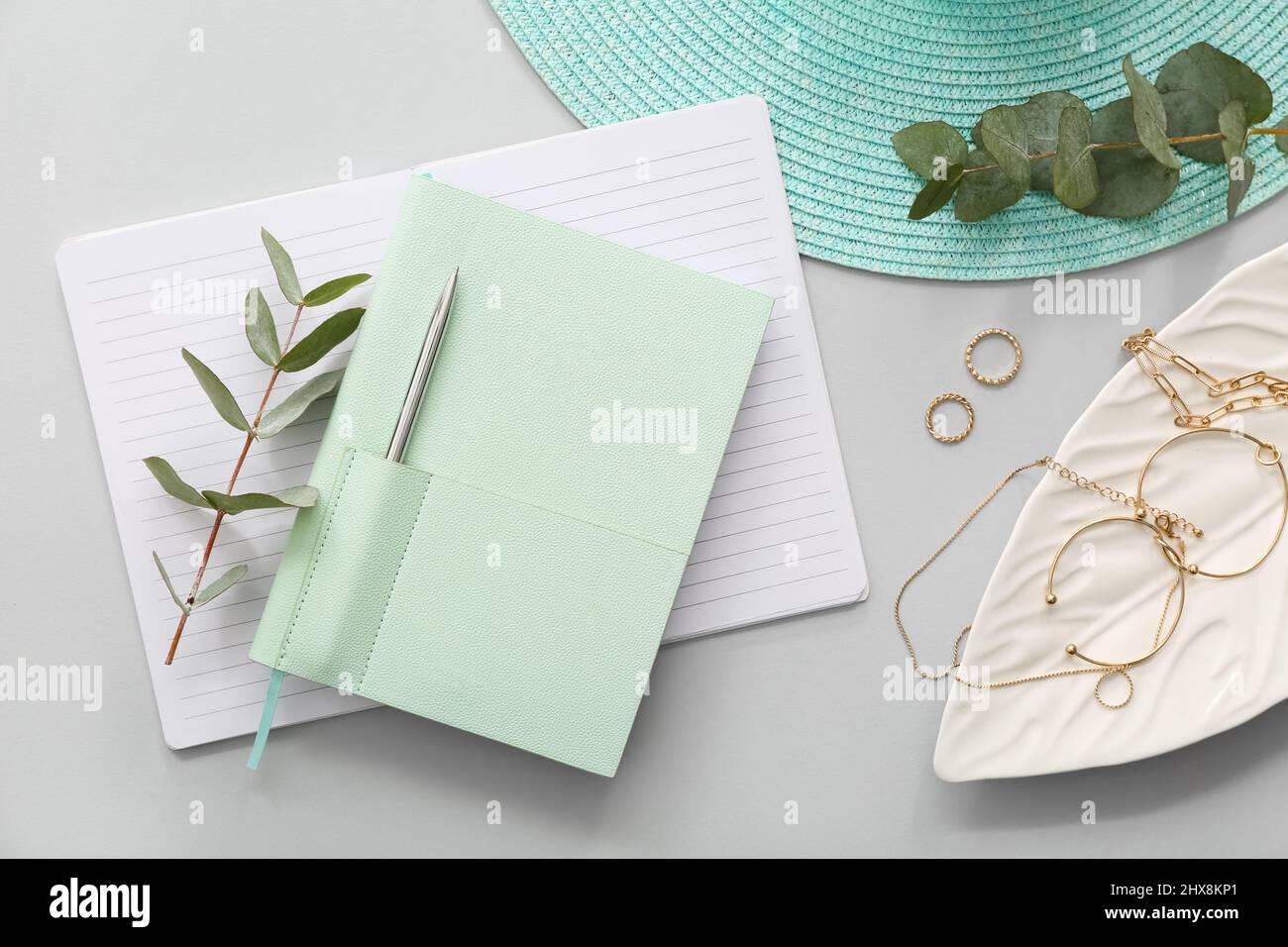 Stylish notebooks with eucalyptus and accessories on light background ...