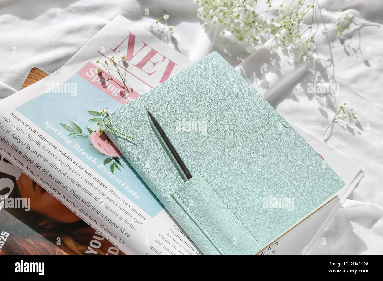 Stylish notebook with newspaper, magazine and gypsophila flowers on ...