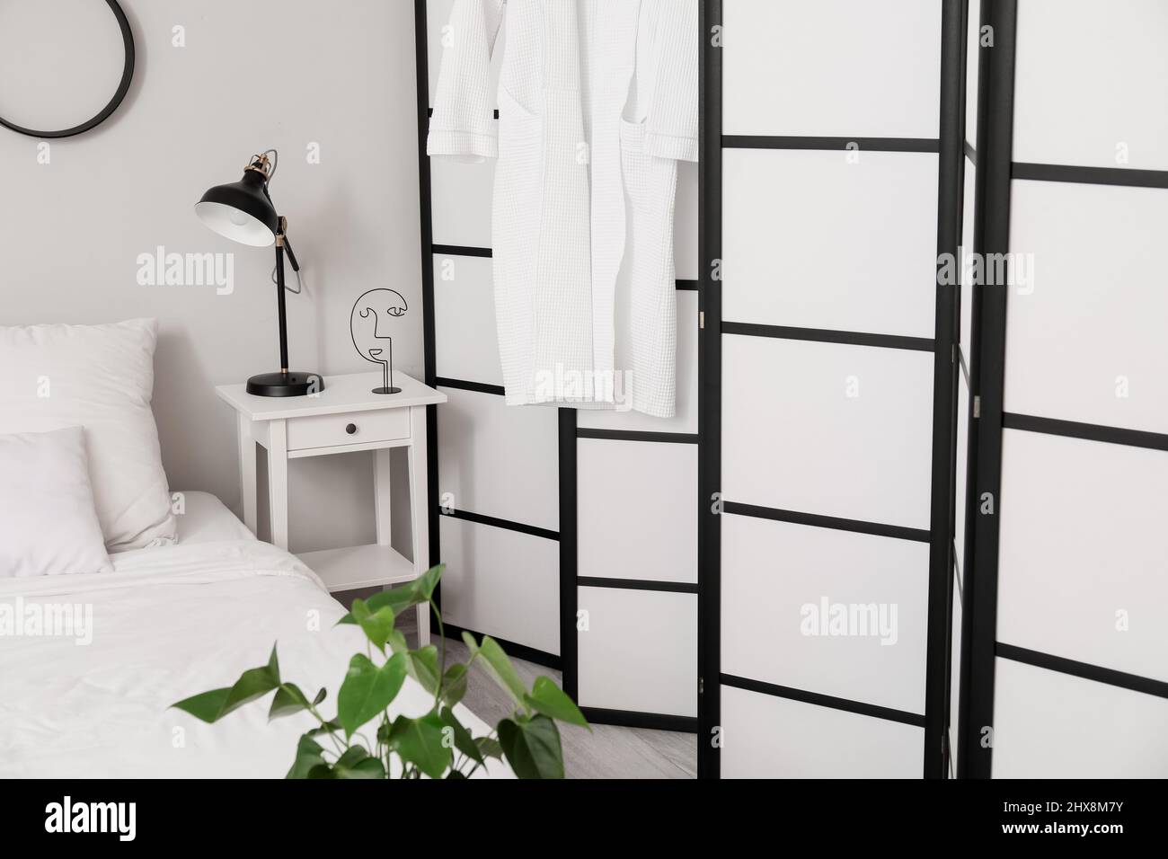 Interior of light bedroom with folding screen, bathrobe and table Stock ...