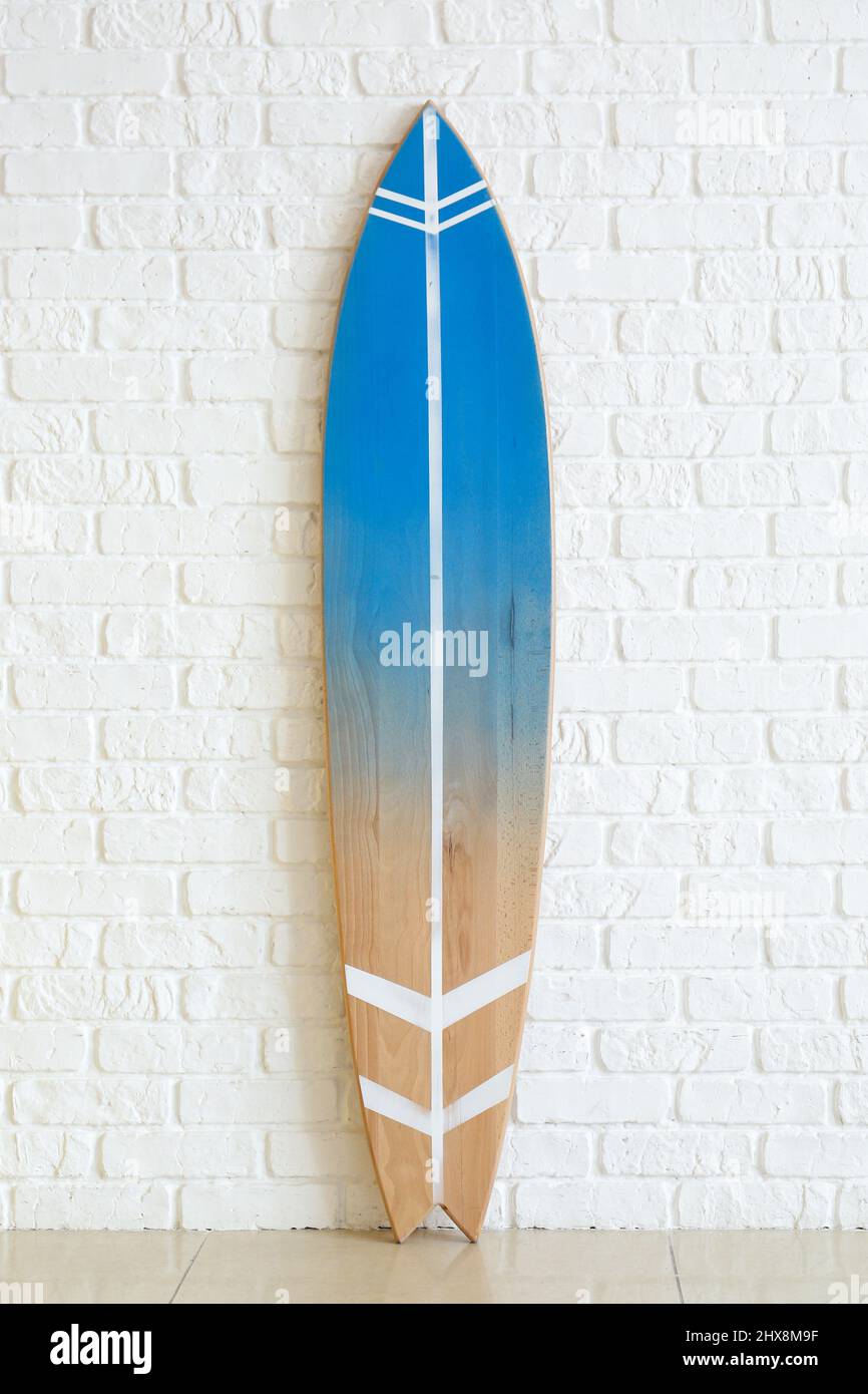 Modern surfboard near white brick wall in room Stock Photo - Alamy