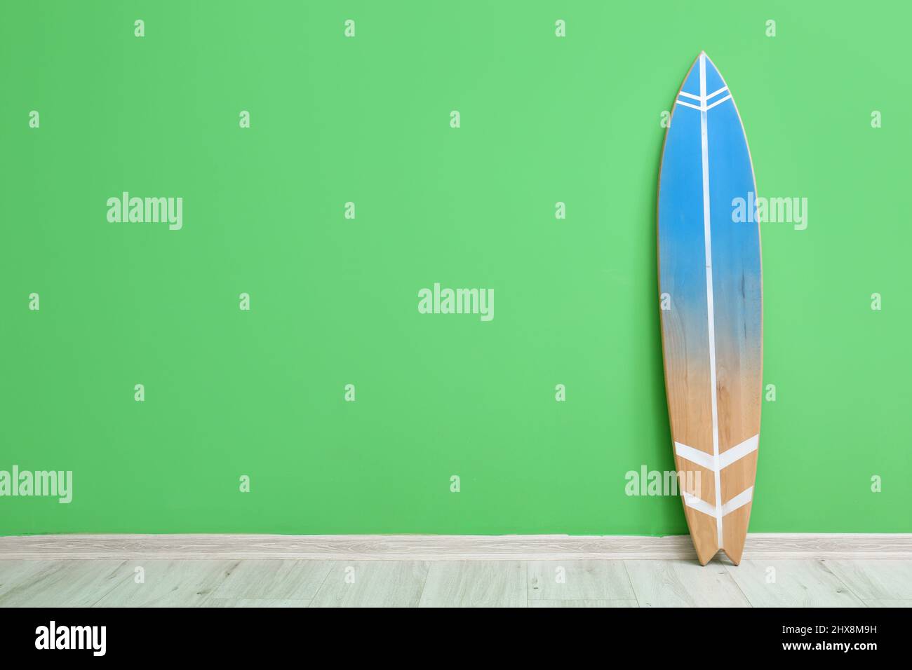 Modern surfboard near green wall in room Stock Photo - Alamy
