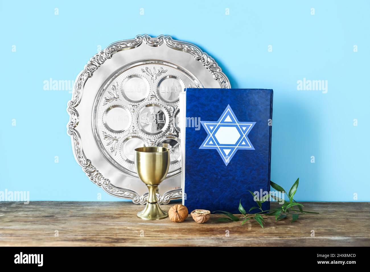 Passover Seder plate with Torah and cup on table against color ...