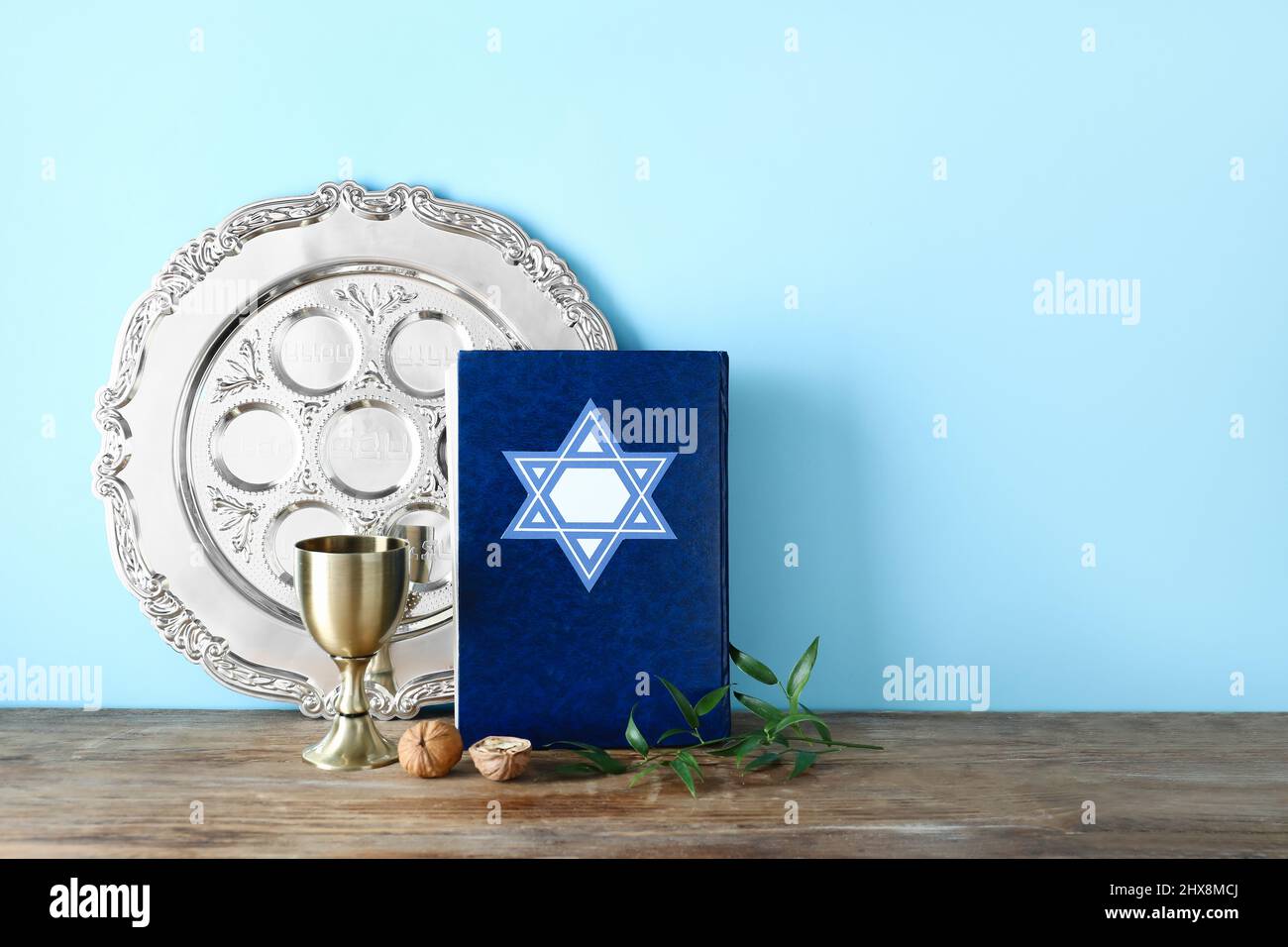 Passover Seder plate with Torah and cup on table against color ...