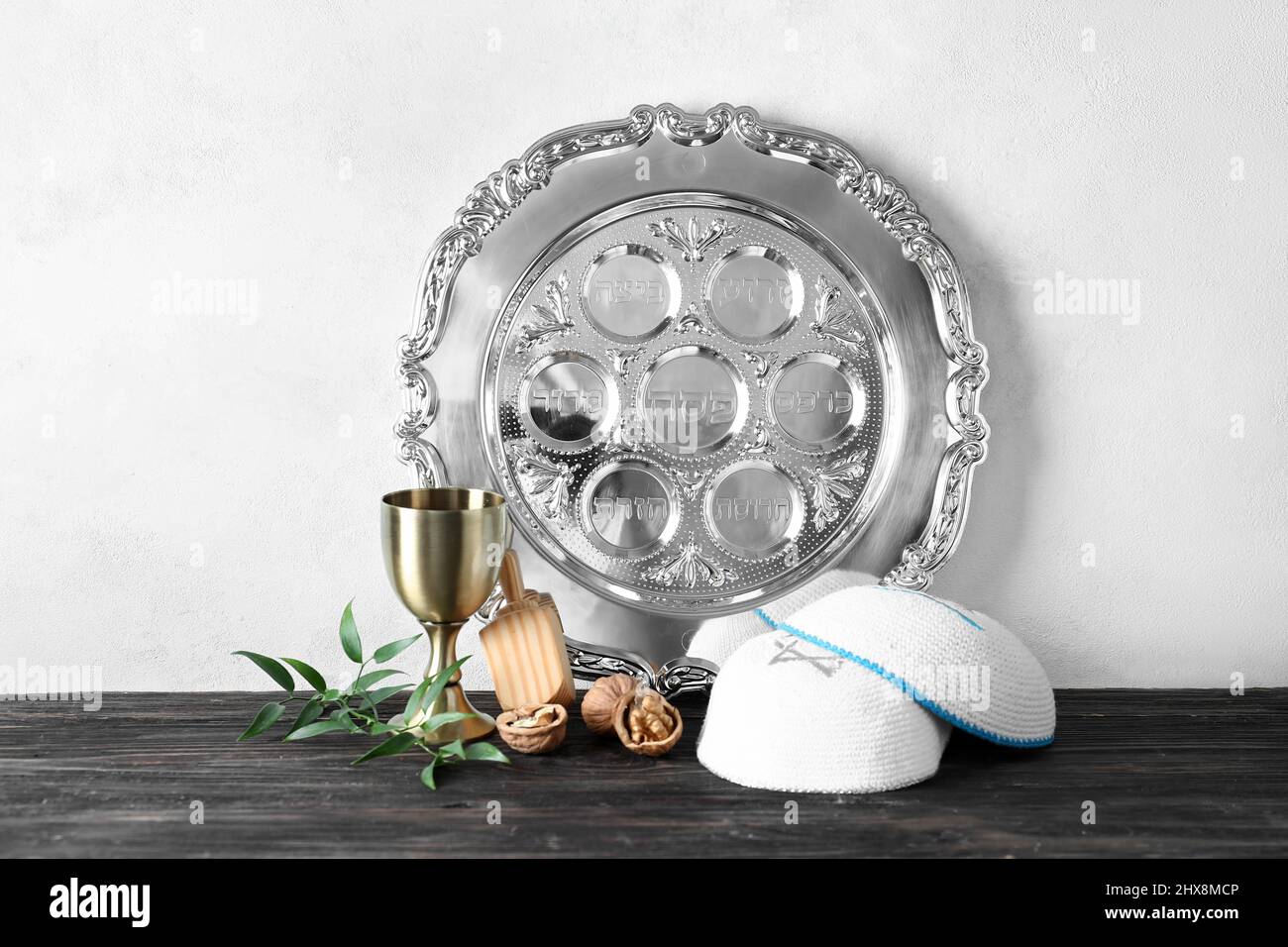 Passover Seder plate with kippah and cup on table against white ...