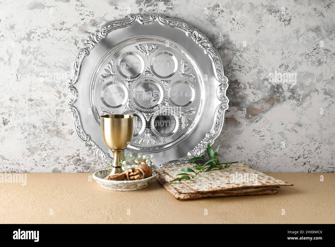 Passover Seder plate with cup of wine, walnuts and matza on table ...