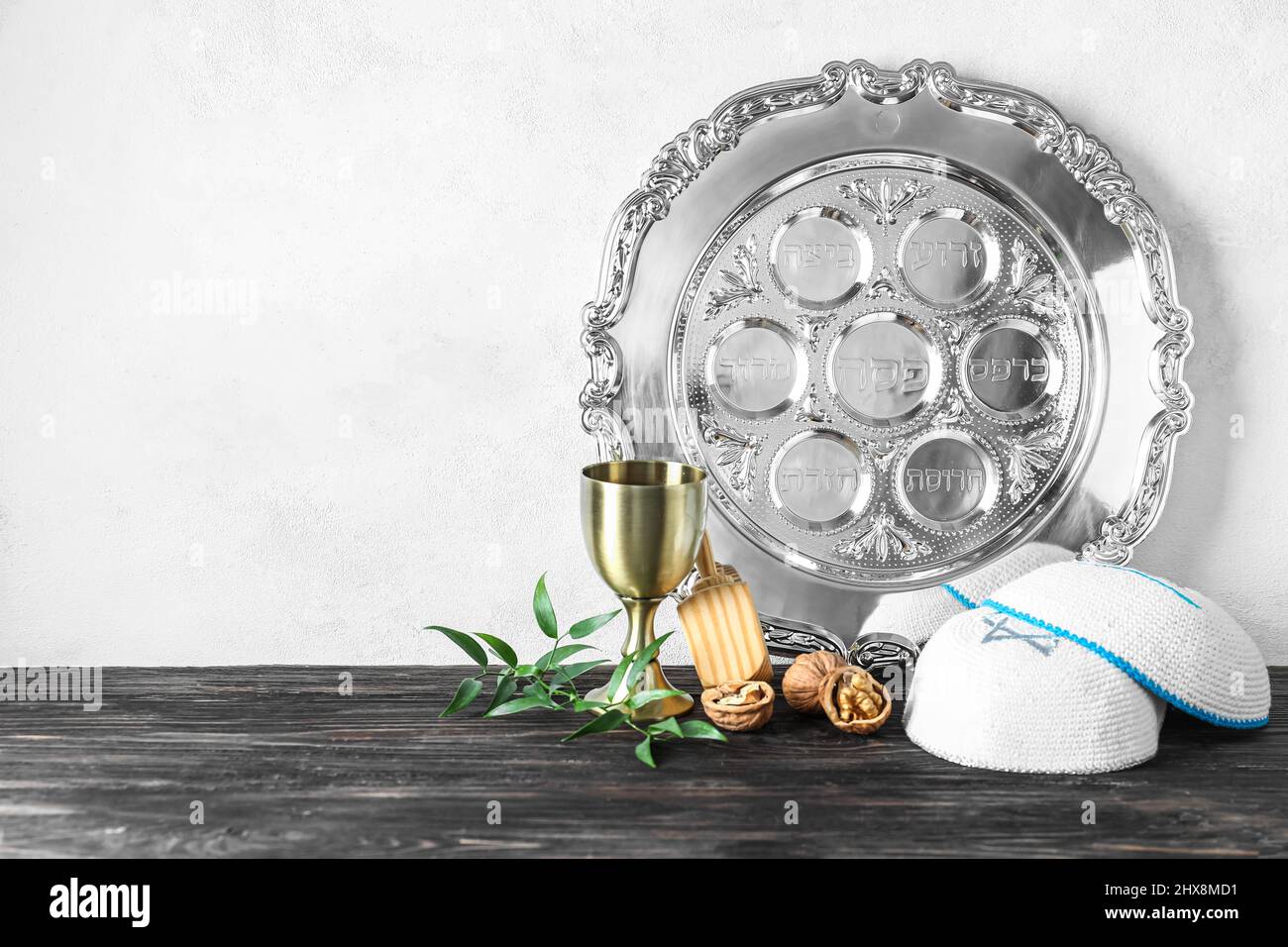 Passover Seder plate with kippah and cup on table against white ...