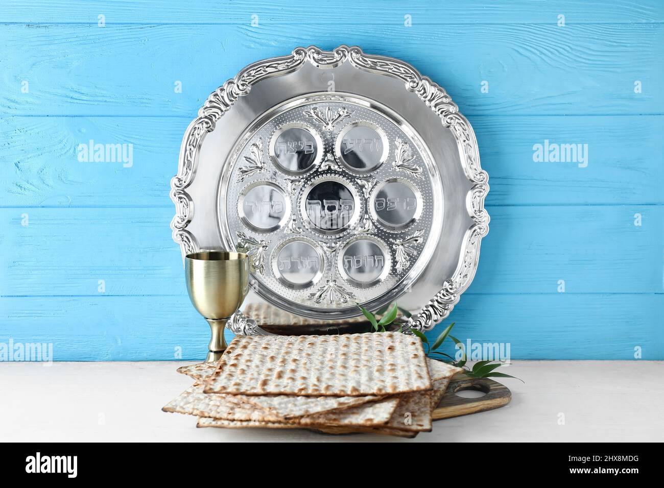 Passover Seder plate with cup of wine and matza on table against color ...