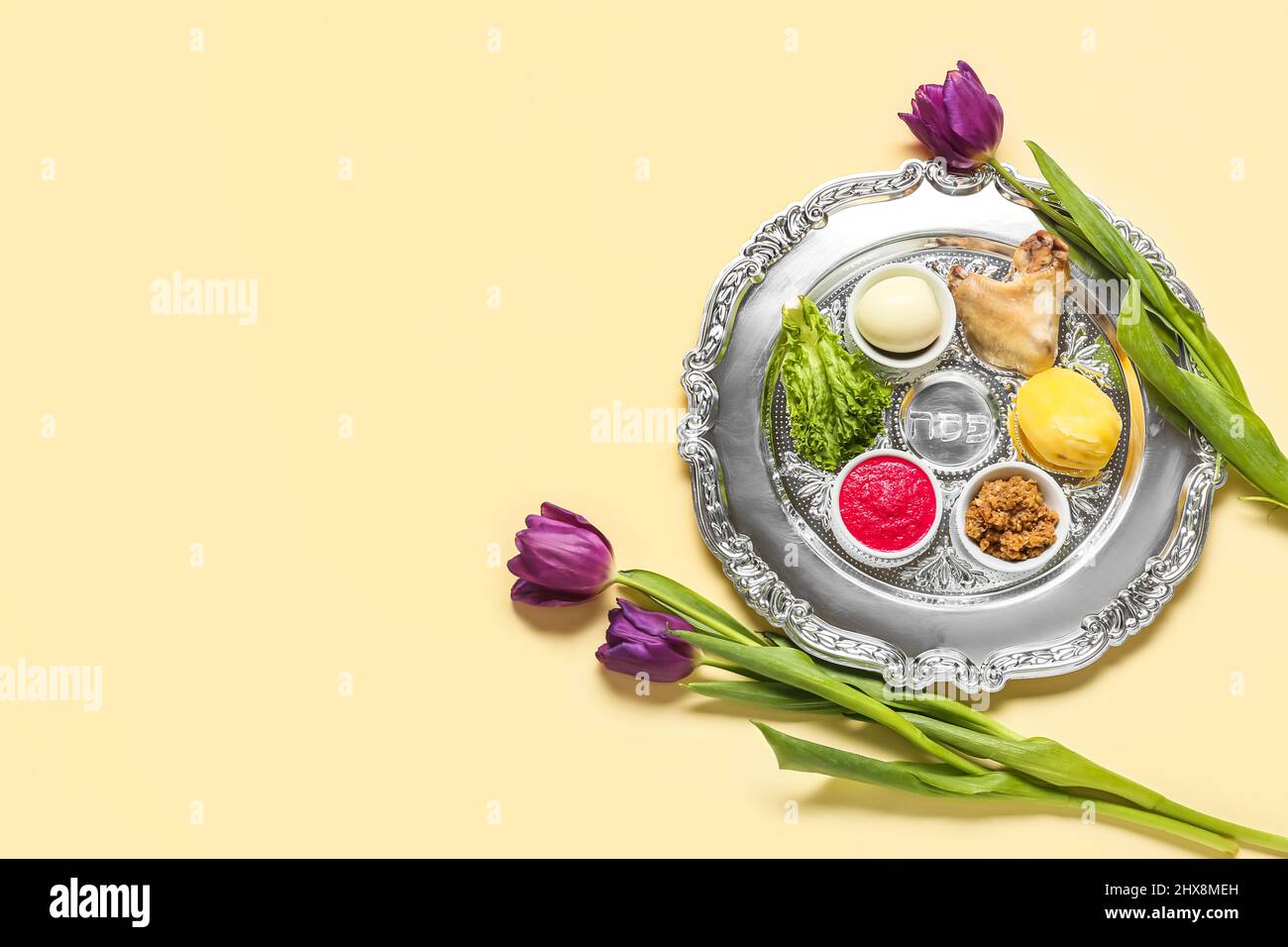 Passover Seder plate with traditional food and tulip flowers on light ...