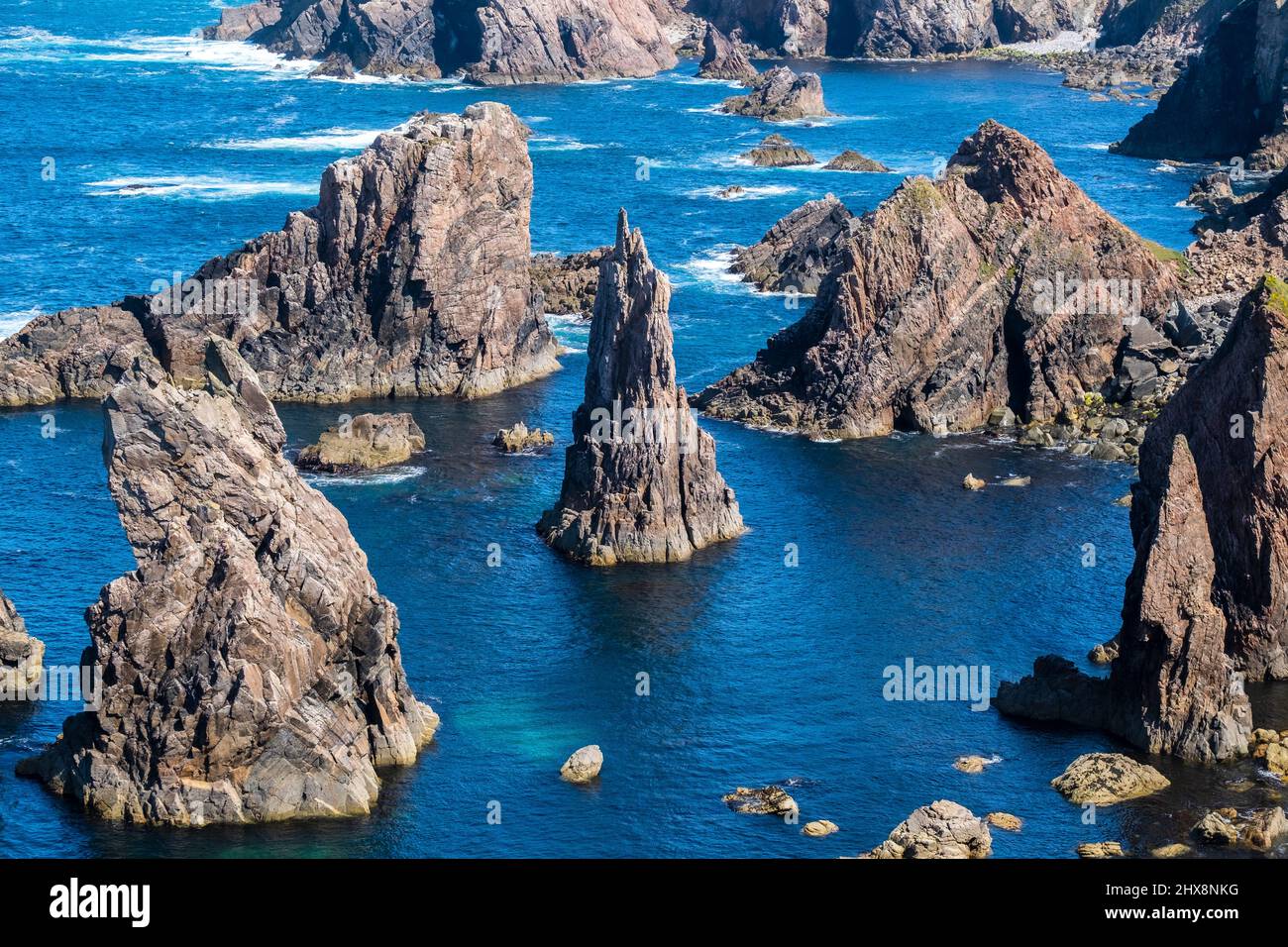 Outcrops of rock rise from the brilliant blue sea in Mangersta Sea ...