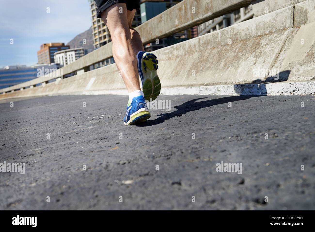 Taming the road. Cropped image of a runners legs as he runs onwards ...