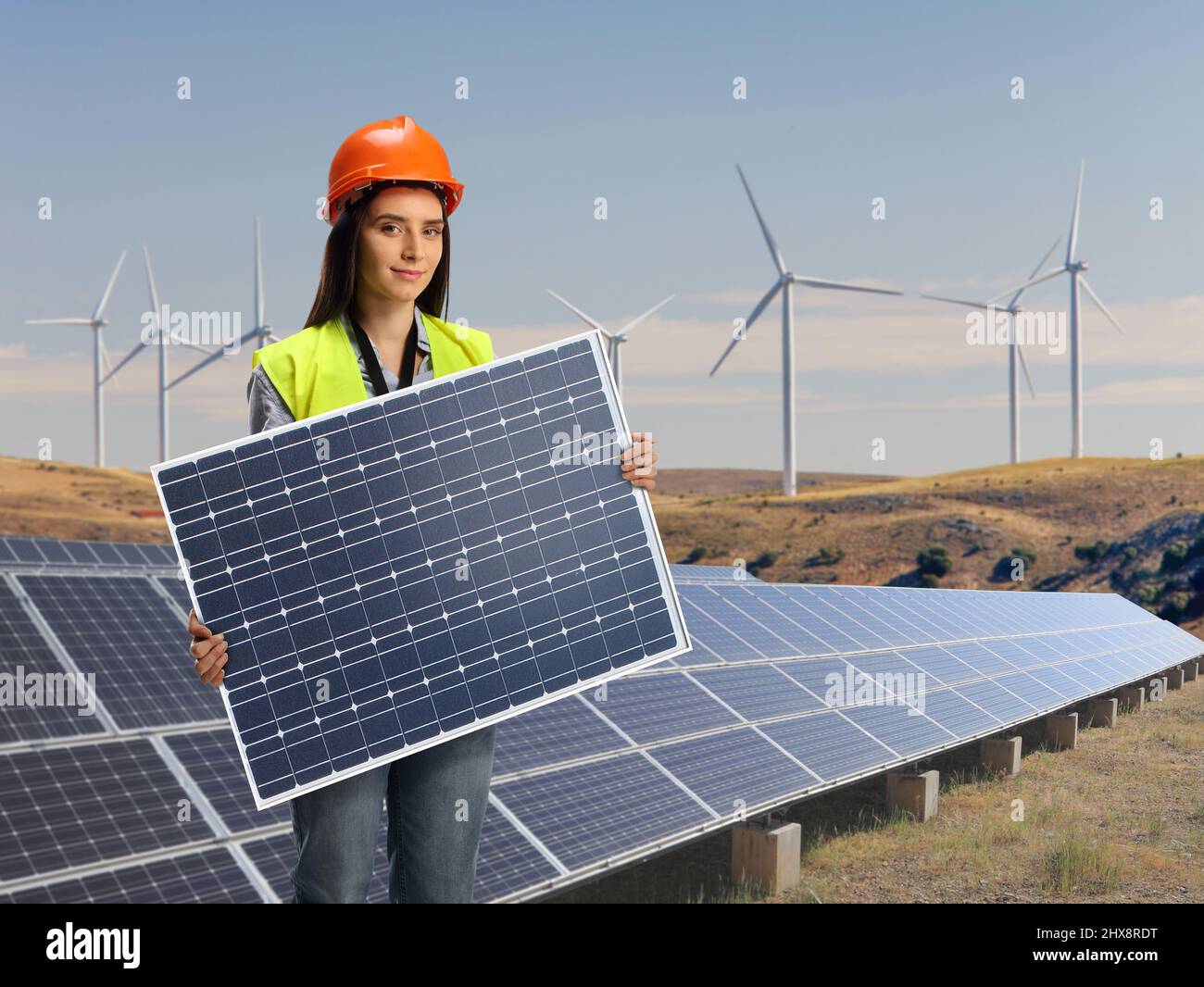 Female engineer on a field for renewable energy with wind turbines and ...
