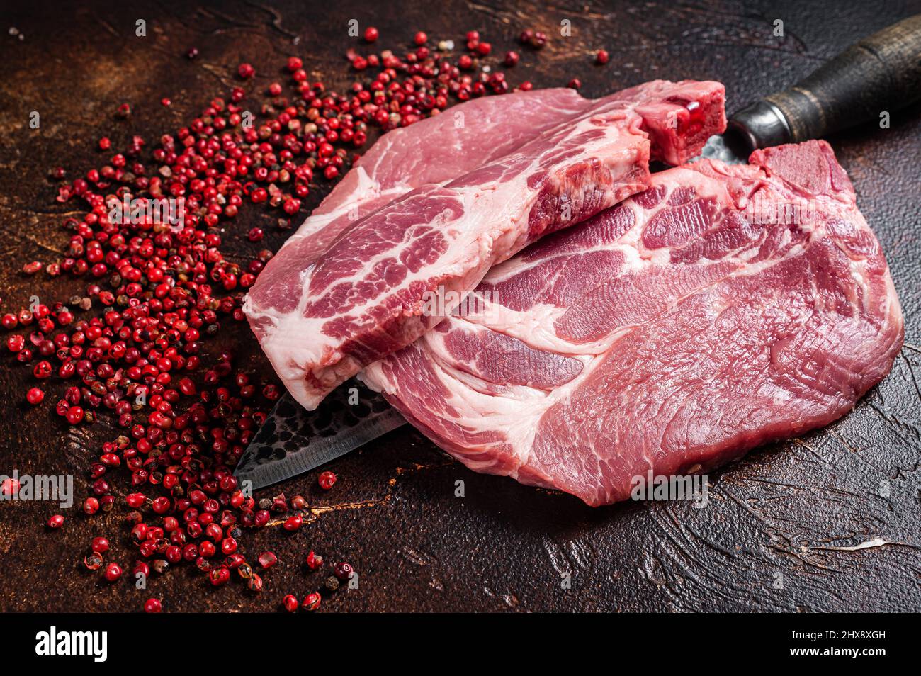 Pork loin steak from raw neck fillet meat on butcher knife. Dark ...