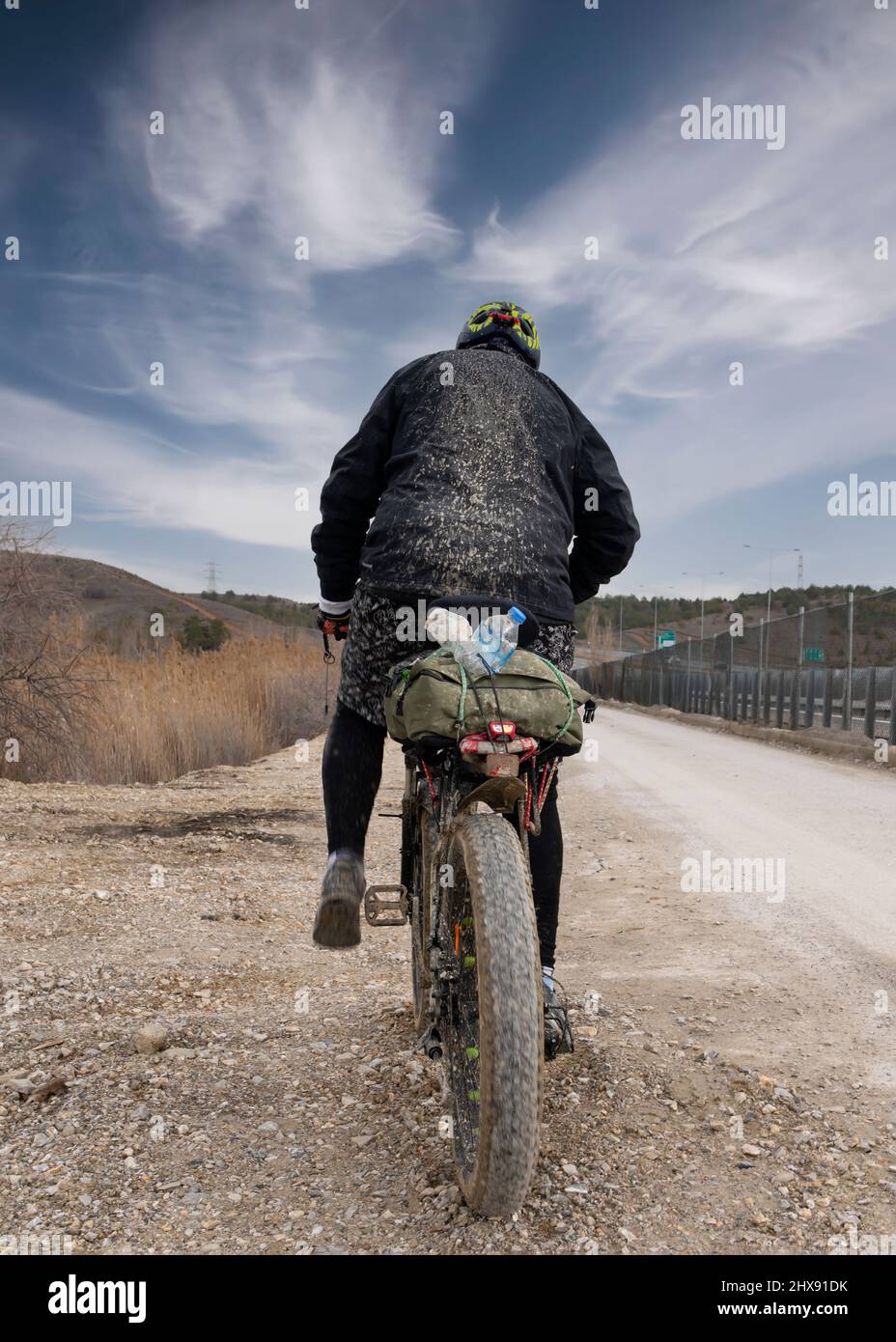 Rear view of cyclist riding on mud dirt road and completely muddy ...