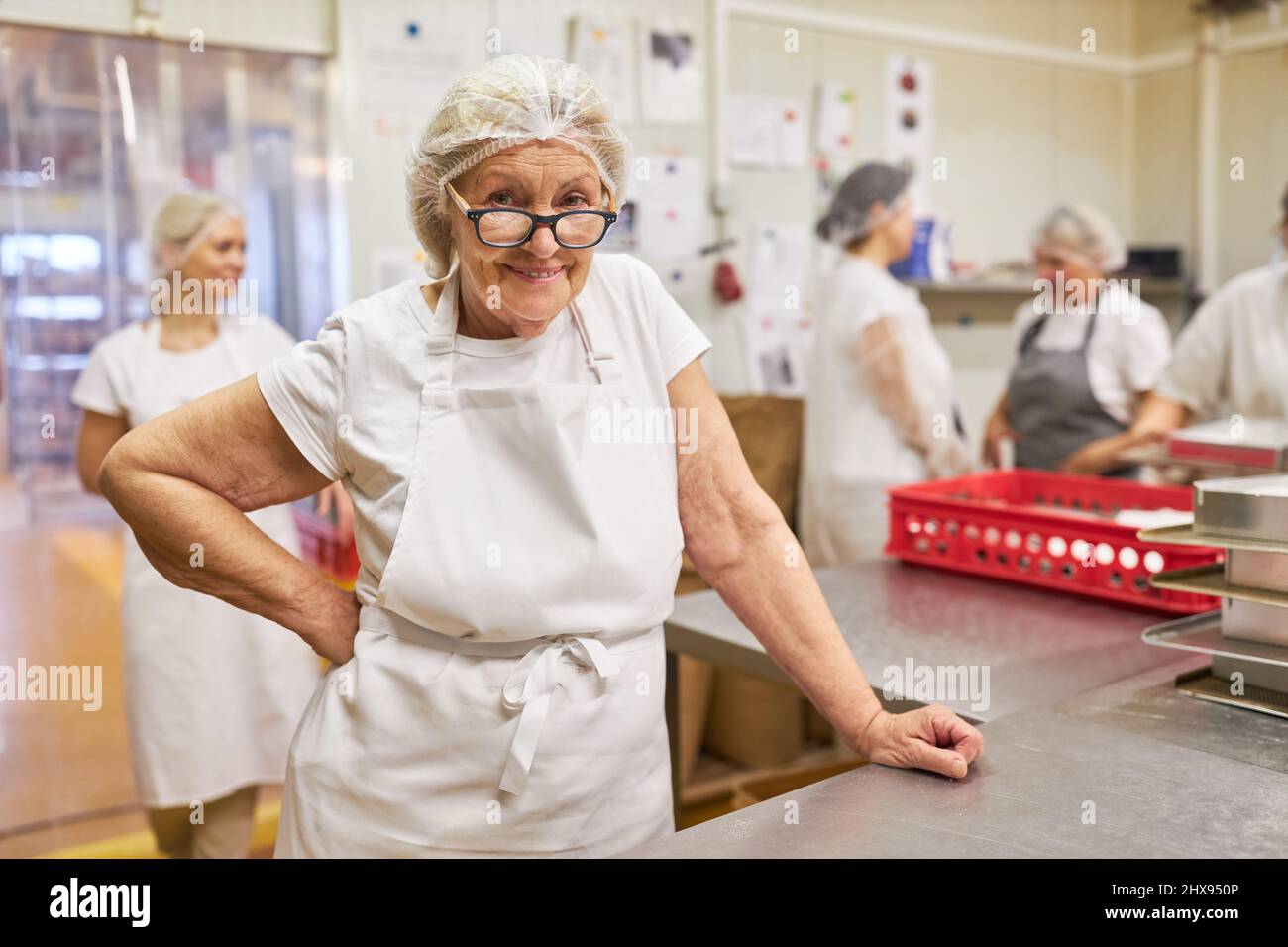 Older woman as a bakery boss with experience stands in the bakery with ...