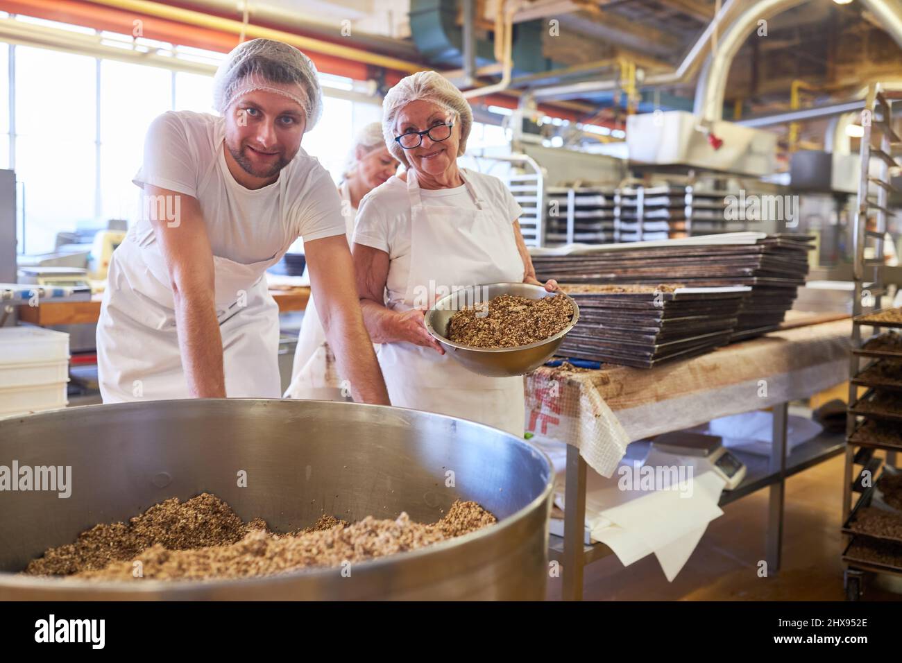 Baker team with grains for wholemeal bread in front of a vat in a ...