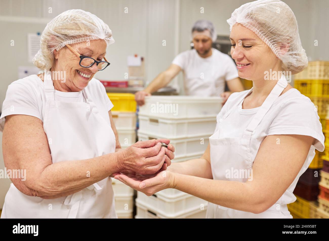 Older woman as a baker baking biscuits together with an apprentice in ...