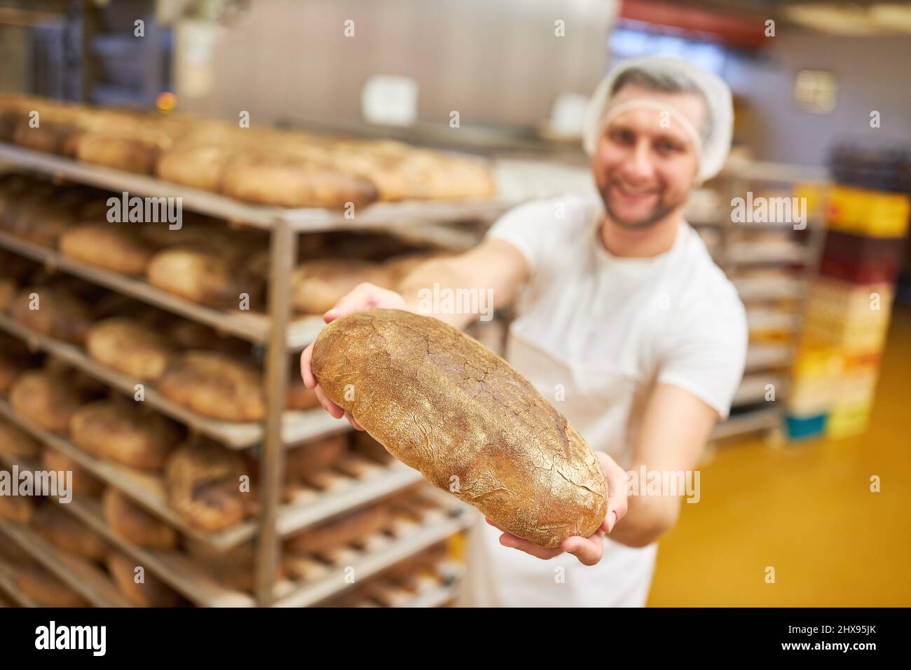 Baker trainee in training proudly shows a ready-baked bread in the ...